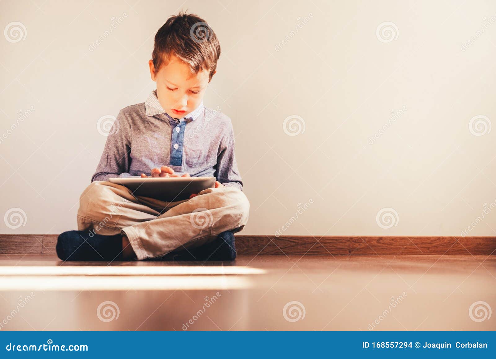 Boy Sitting on the Floor with a Digital Tablet in His Hands, Using it ...