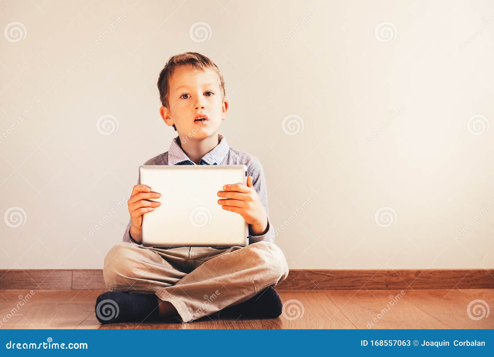 Boy Sitting on the Floor with a Digital Tablet in His Hands, Using it ...