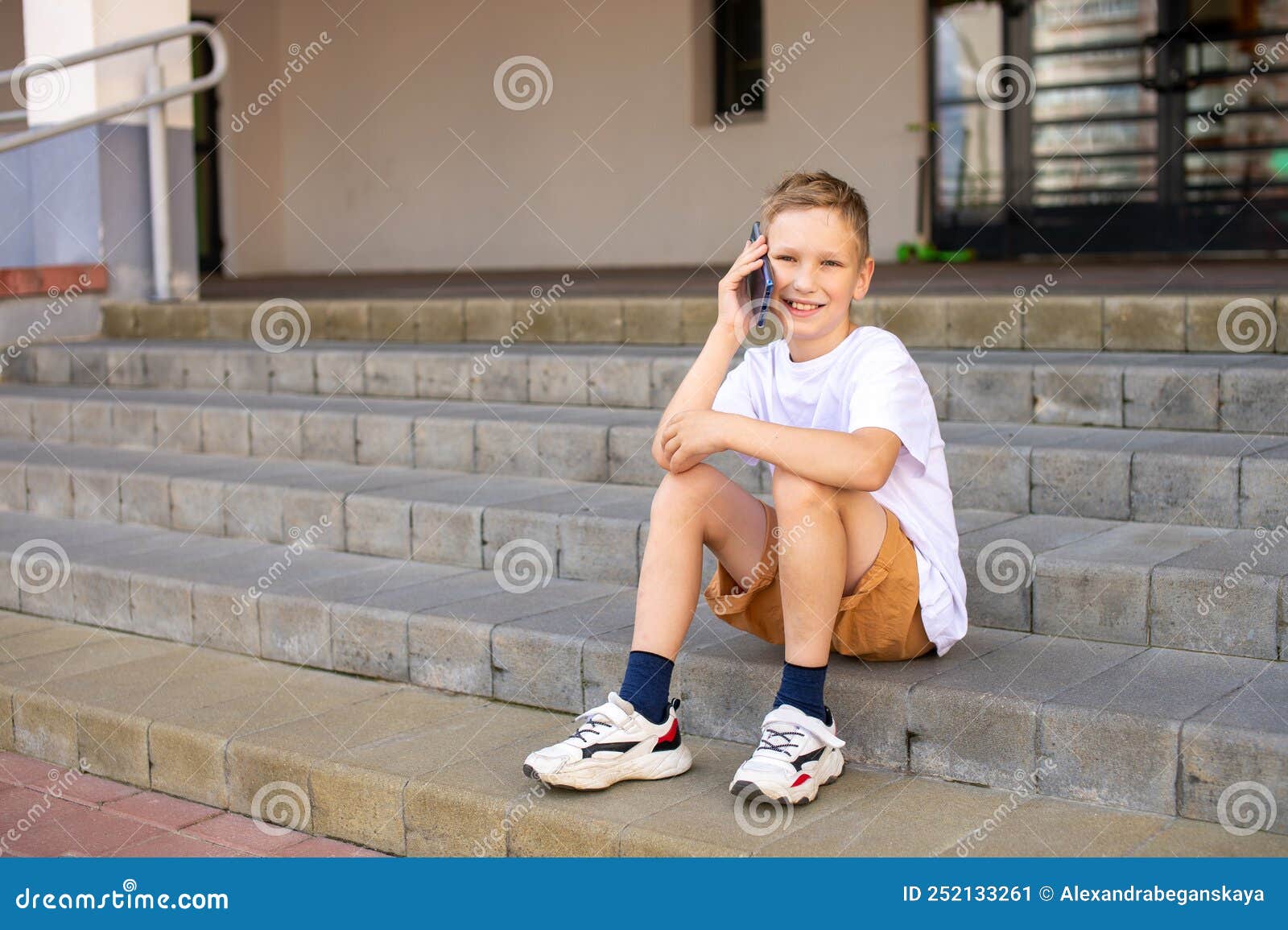 The Boy is Sitting on the Steps and Talking on the Phone Stock Image ...