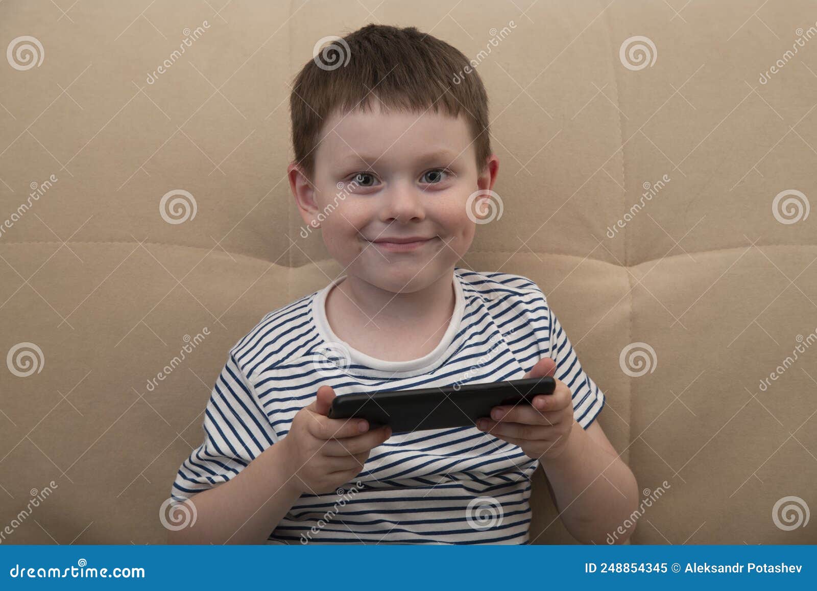 A Boy with a Smartphone on the Couch Playing Games Stock Image - Image ...