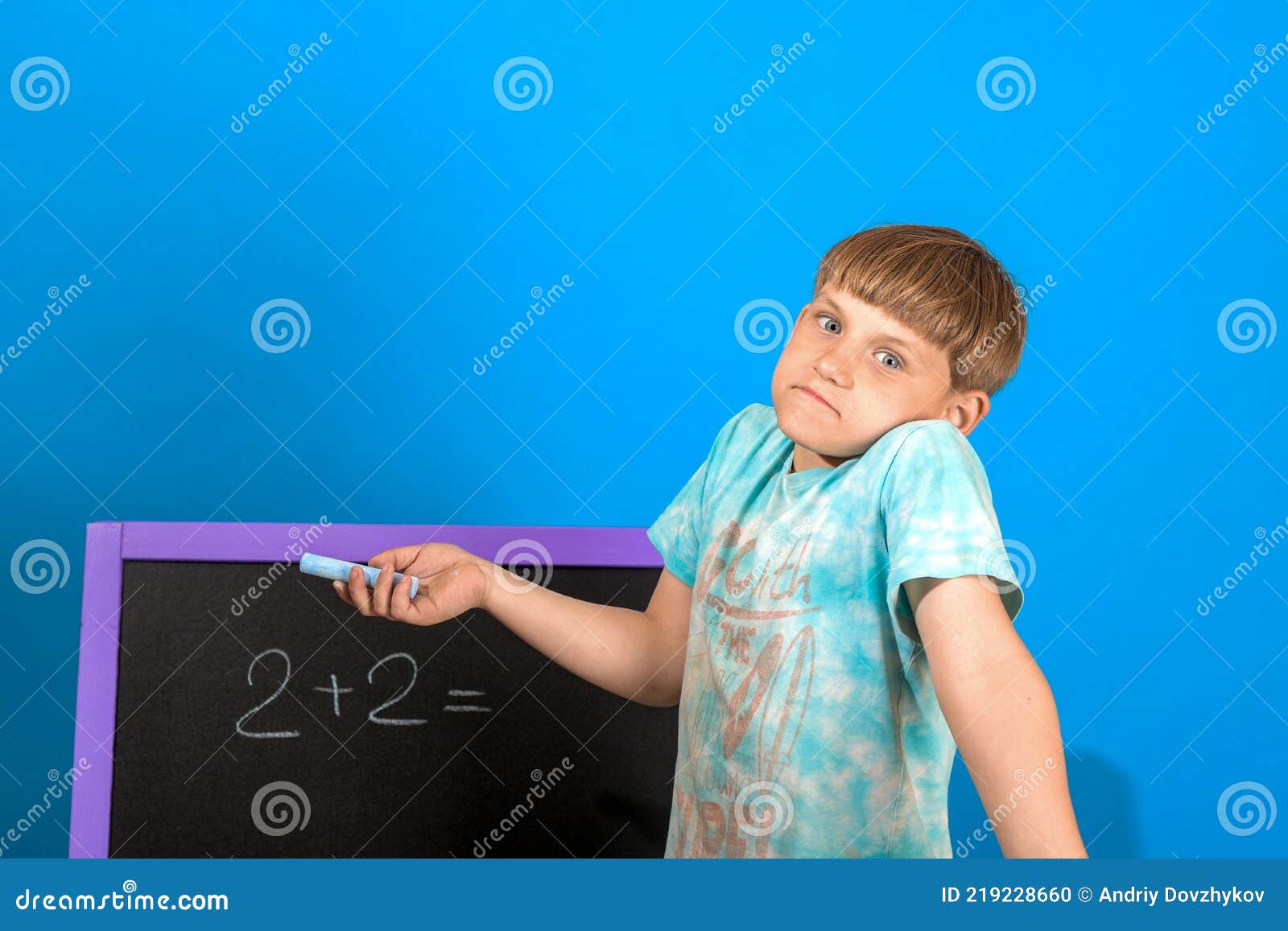 The Boy Solves the Math Equation 2 + 2 Written on the Blackboard. the ...