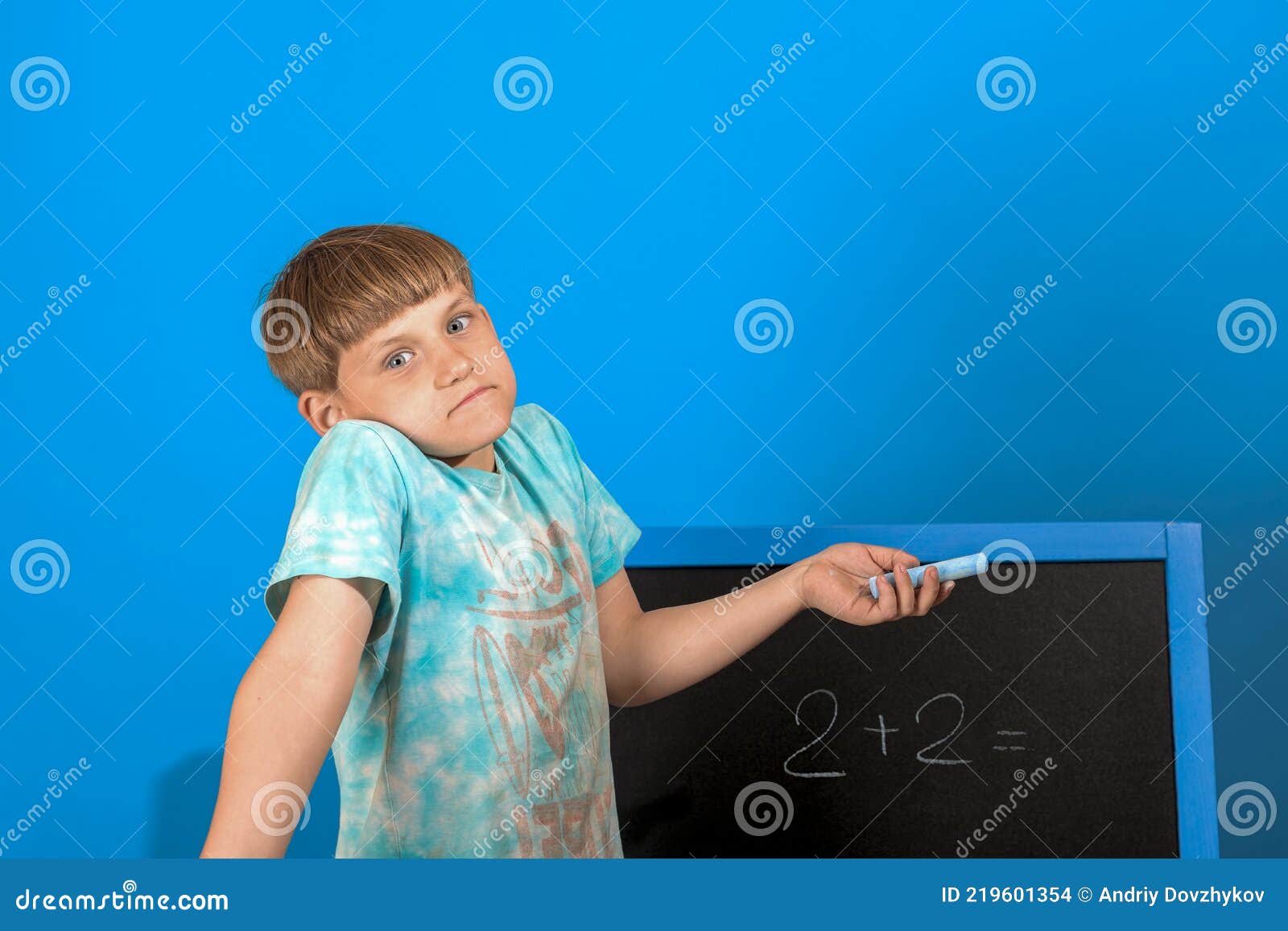 The Boy Solves the Math Equation 2 + 2 Written on the Blackboard. the ...
