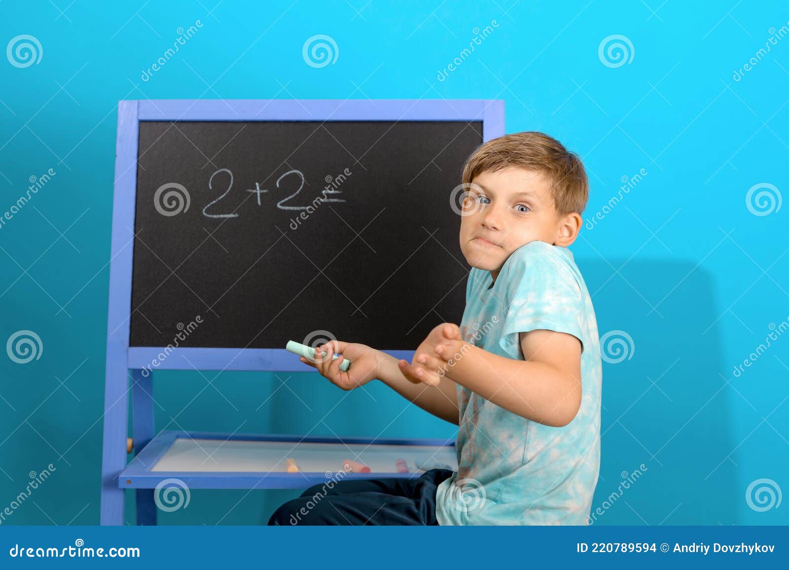 The Boy Solves the Math Equation 2 + 2 Written on the Blackboard. the ...