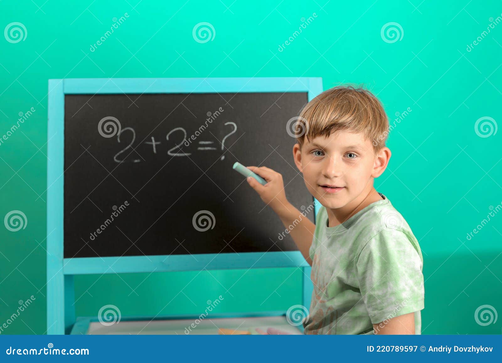 The Boy Solves the Math Equation 2 + 2 Written on the Blackboard. the ...