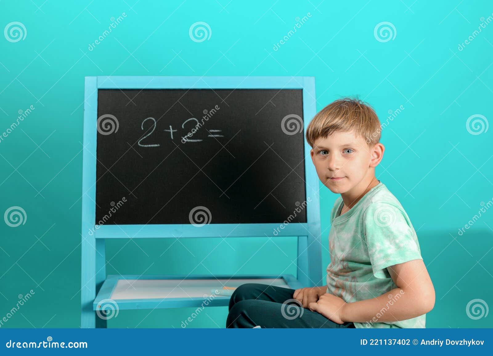 The Boy Solves the Math Equation 2 + 2 Written on the Blackboard. the ...