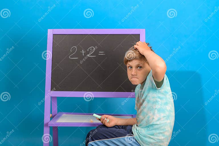 The Boy Solves the Math Equation 2 + 2 Written on the Blackboard. the ...