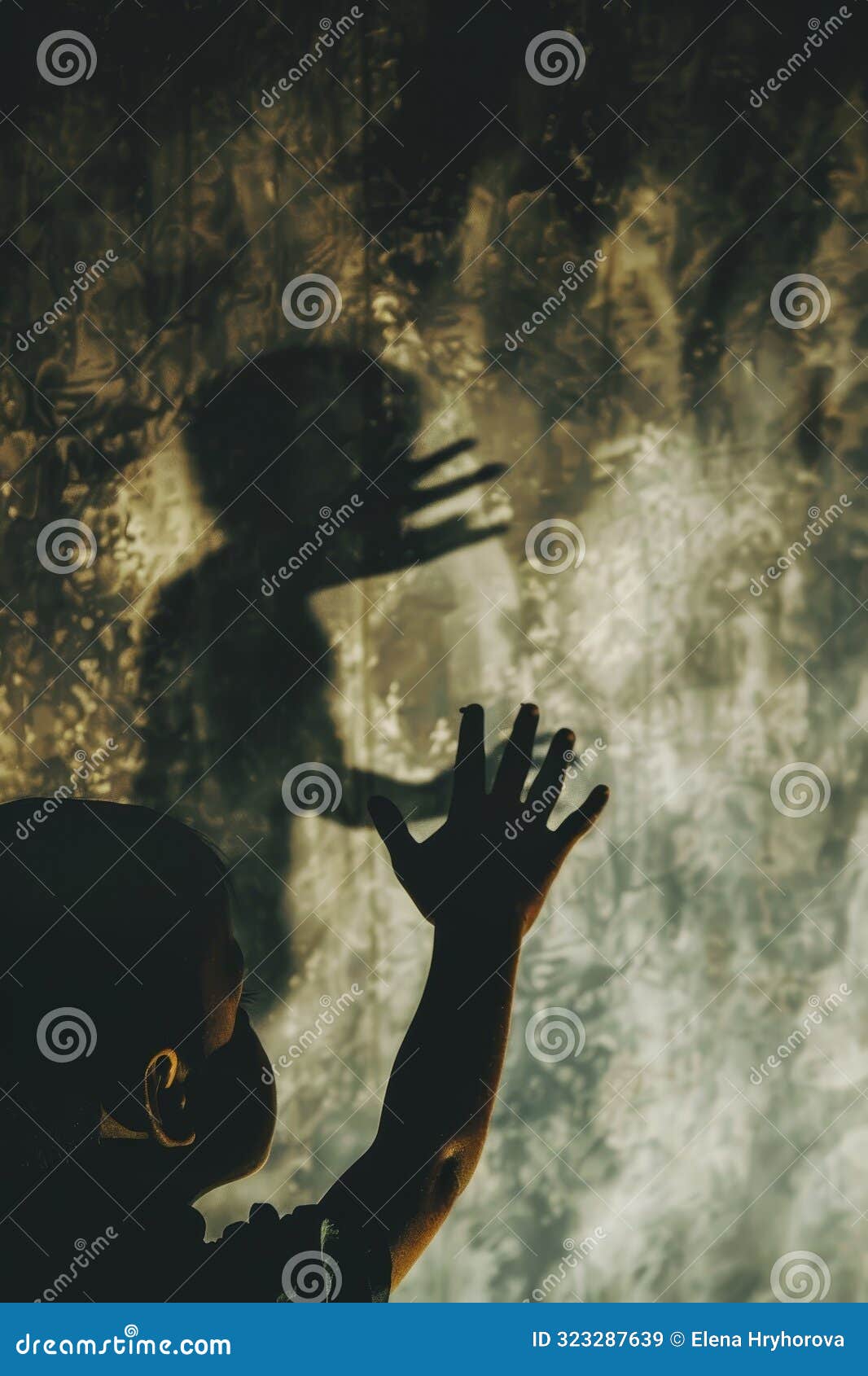 A Boy Standing in Front of a Wall with His Hand Raised, Casting a ...