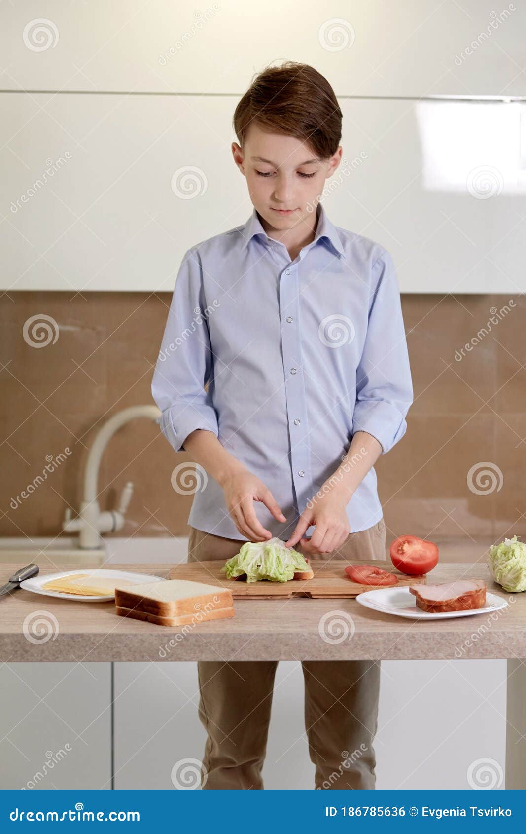 A Boy Stands in the Kitchen in Front of the Table and Prepares a ...