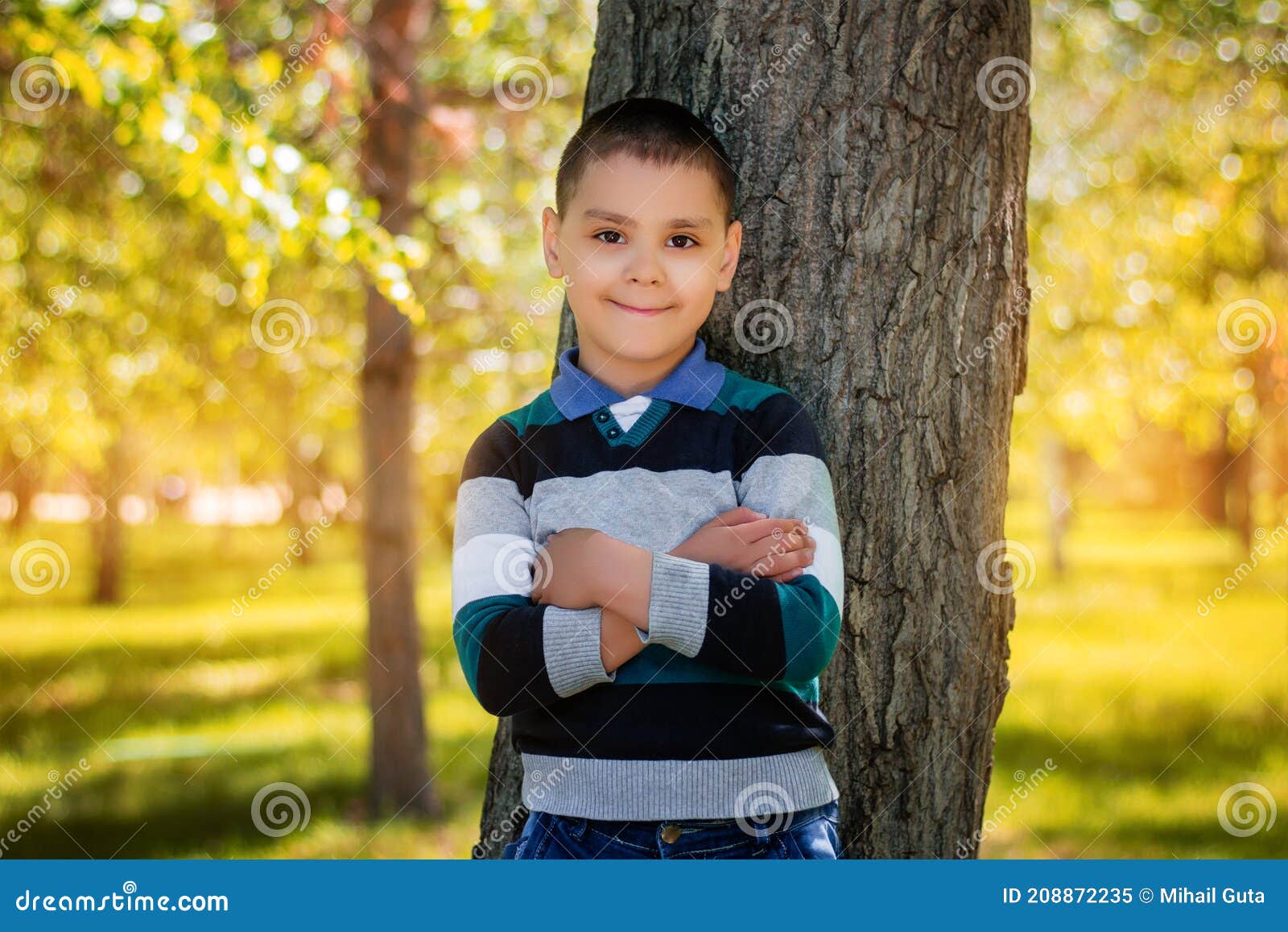 A Boy Stands Leaning Against a Tree in a Park Stock Image - Image of ...