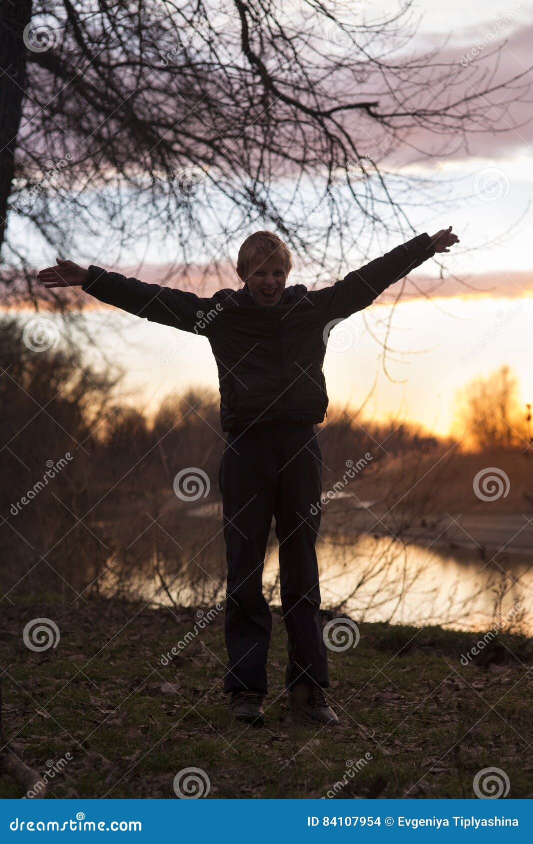 Boy stands in the sunset stock photo. Image of silhouette - 84107954
