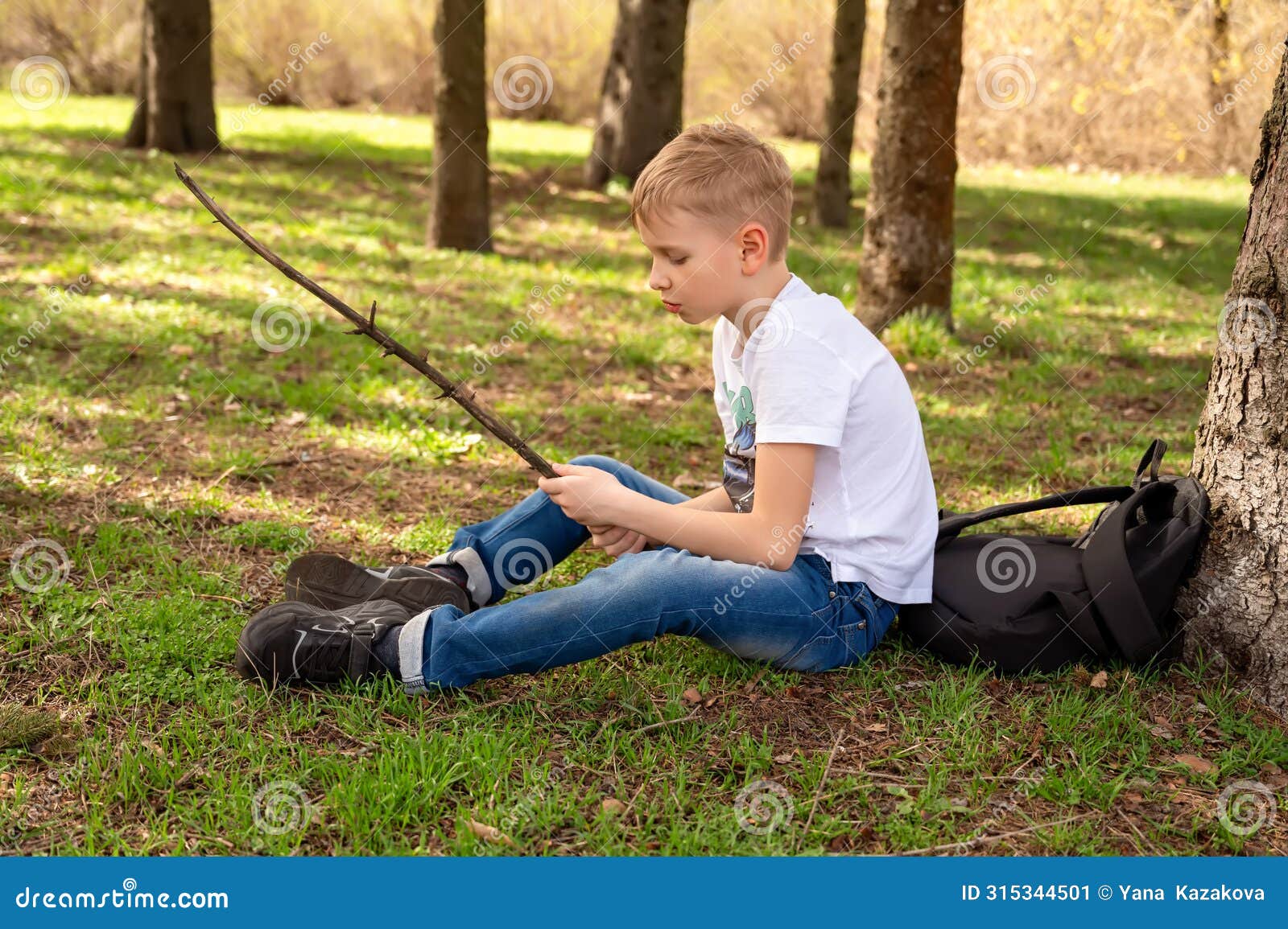 A Boy with a Stick Sits on the Grass in Spring Park Stock Image - Image ...