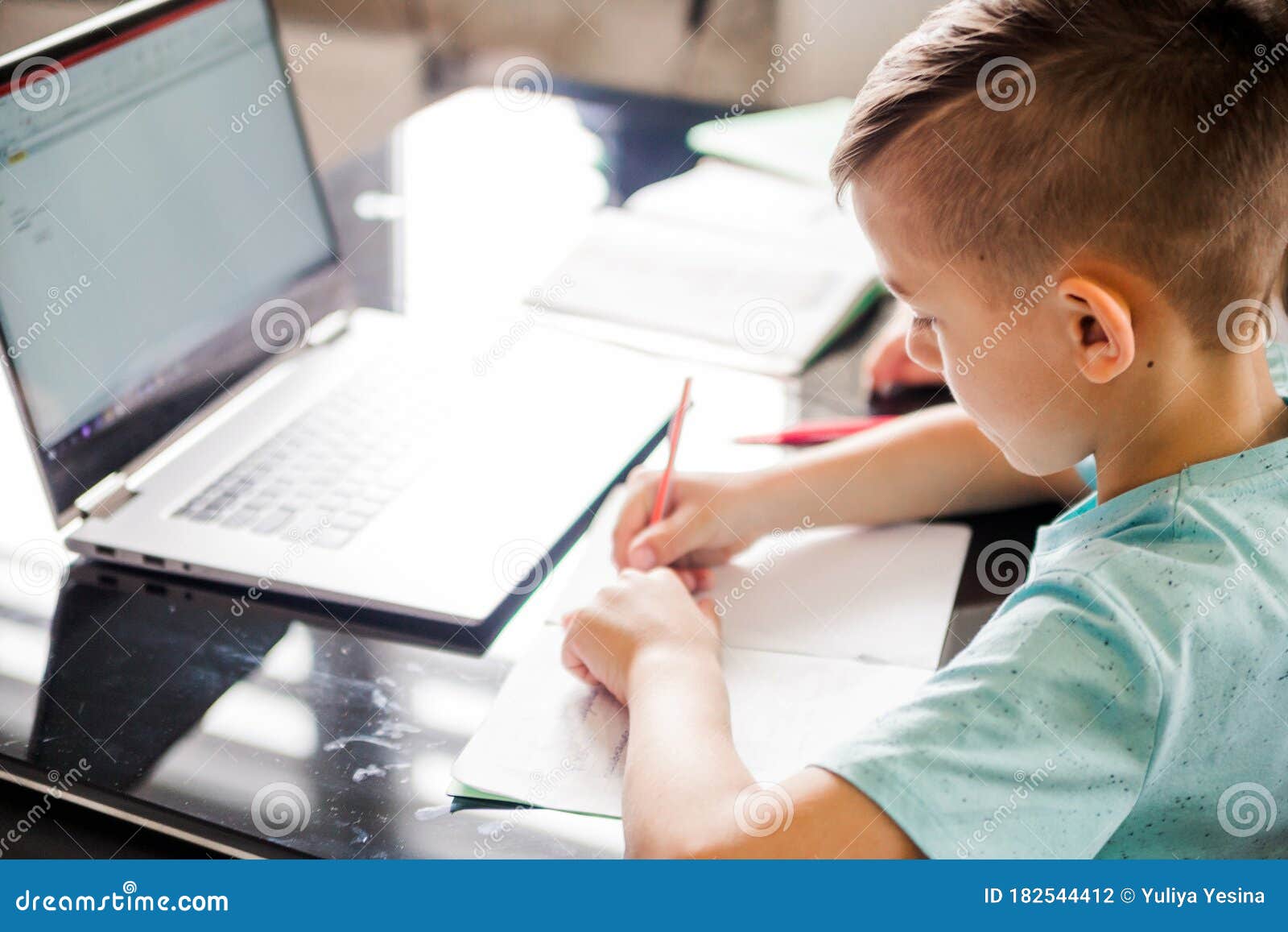 The Boy is Studying at Home. Sits at a Table with Textbooks, a Laptop ...