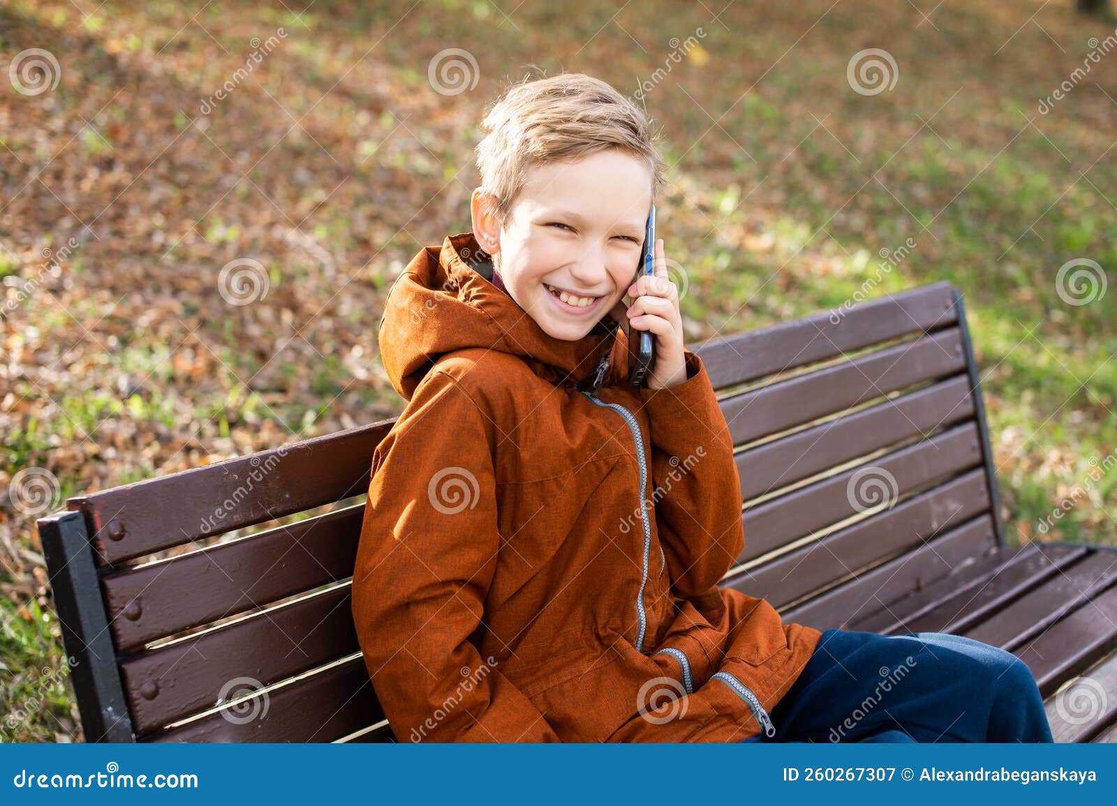 The Boy is Talking on the Phone Sitting on a Bench and Laughing Stock ...