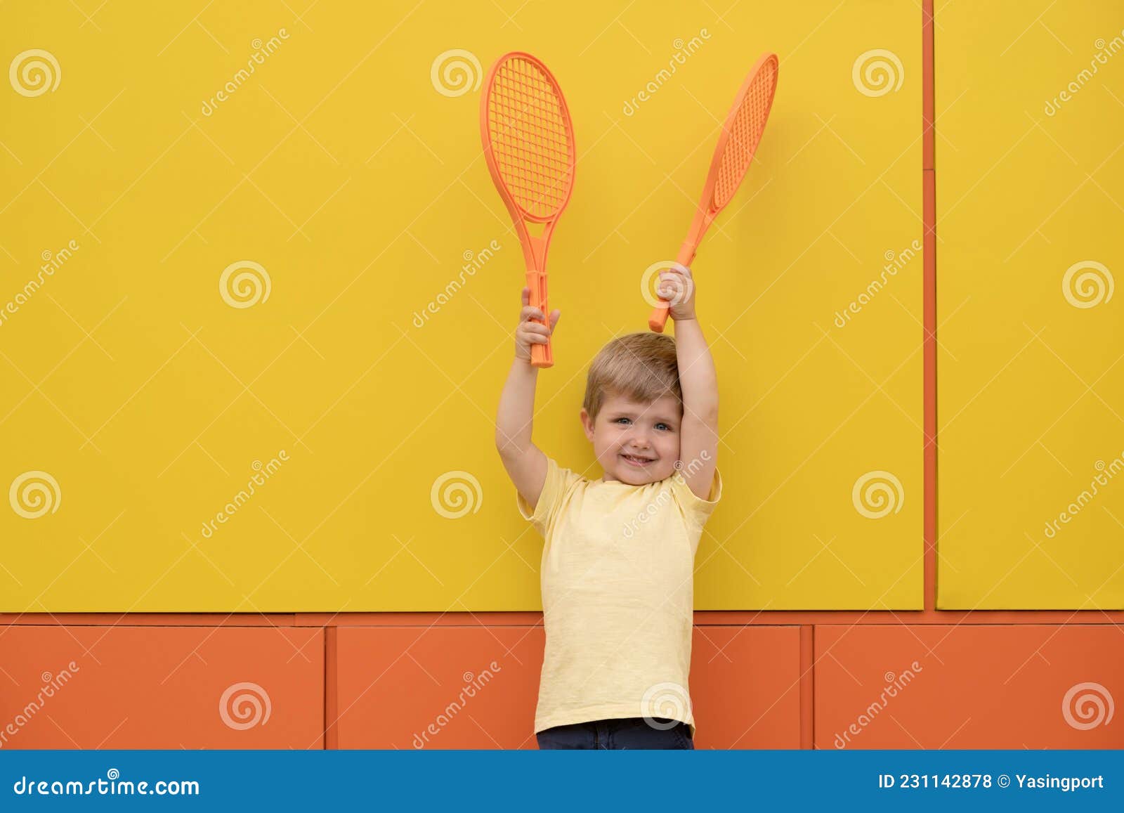 Boy with Tennis Rackets Against Yellow Wall Stock Photo - Image of ball ...
