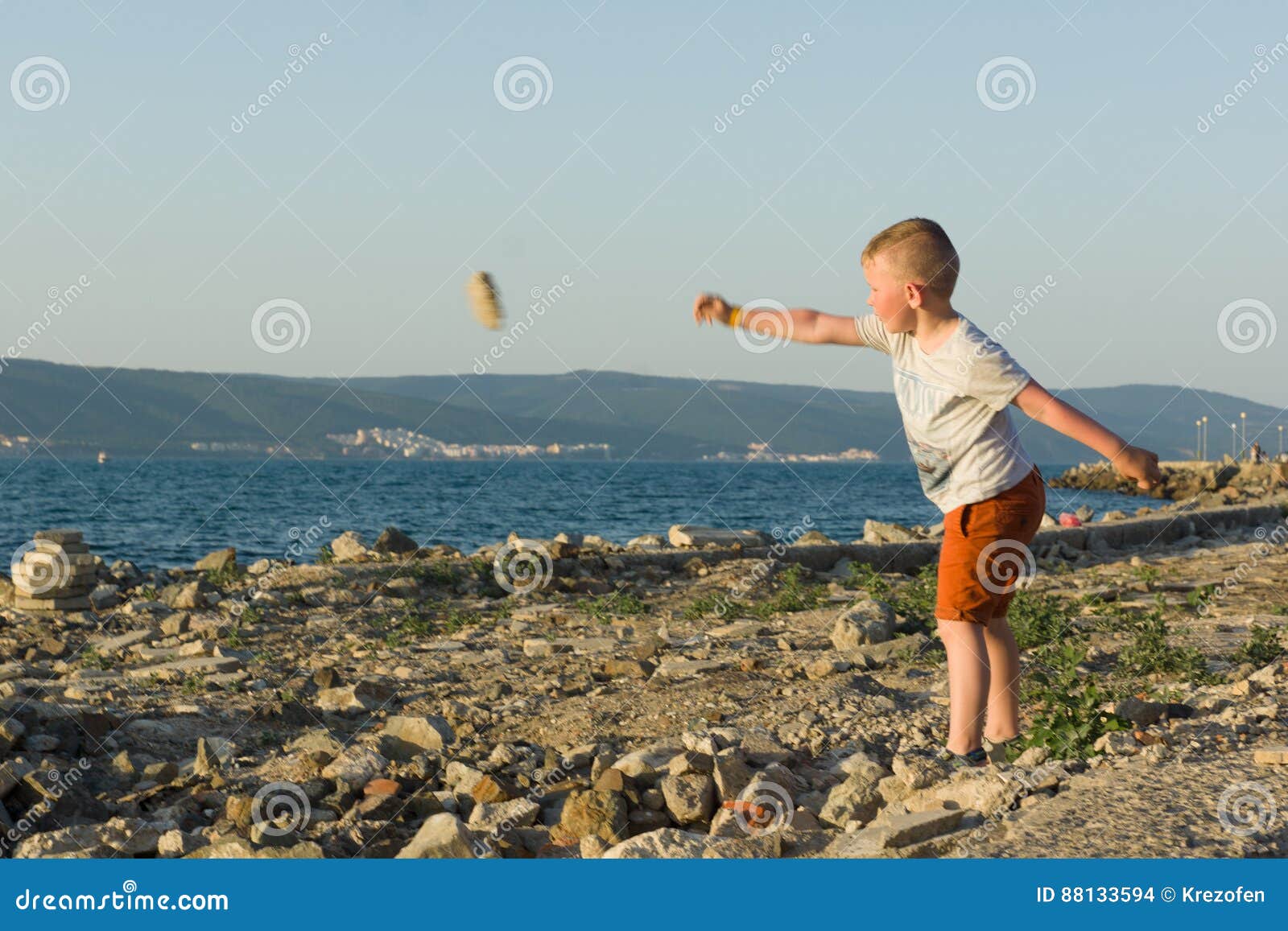 Boy throws stones at sea stock photo. Image of child - 88133594
