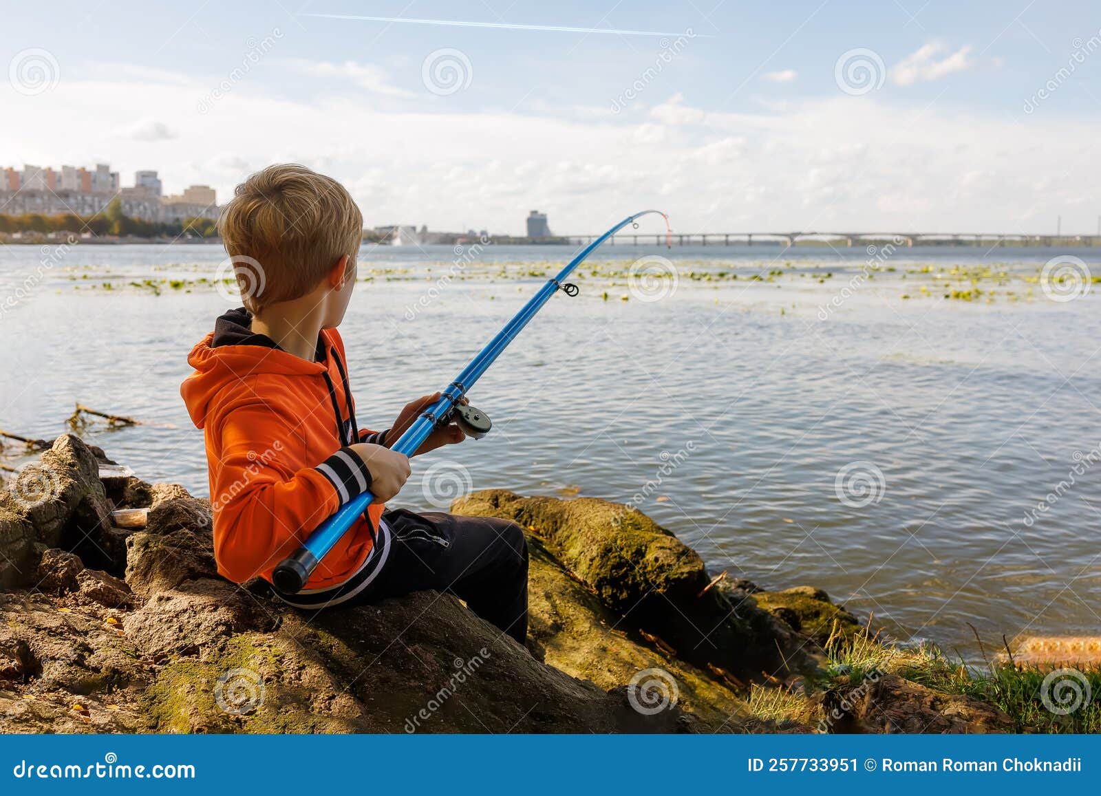 The Boy is Trying To Pull the Fish Out of the River with the Help of a ...