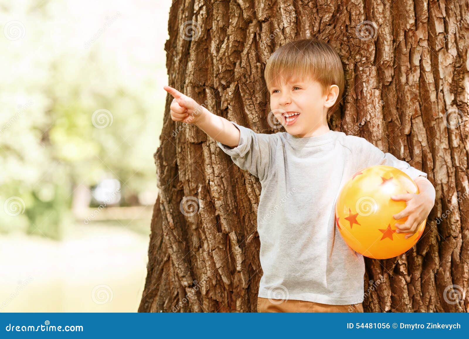 Boy Under Tree with Rubber Ball Pointing Upwards Stock Photo - Image of ...
