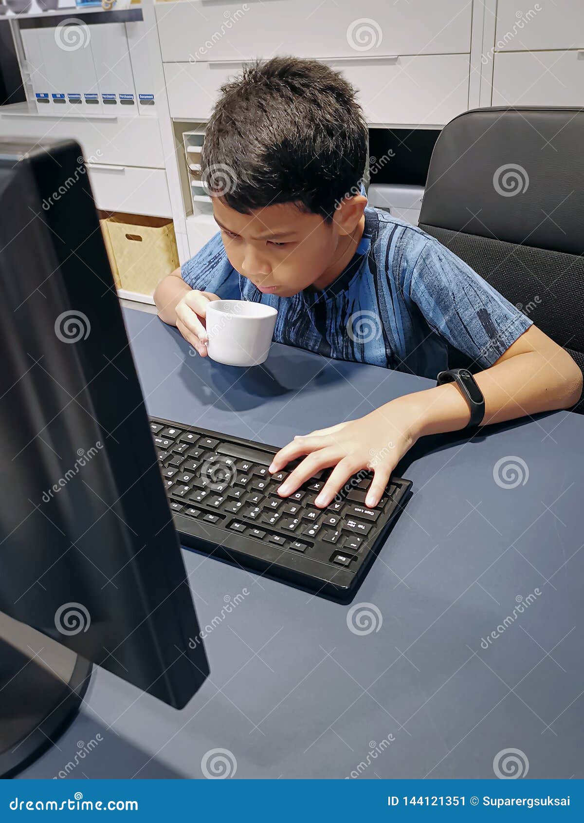 Boy Using Computer while Drinking a Cup of Tea Stock Image - Image of ...
