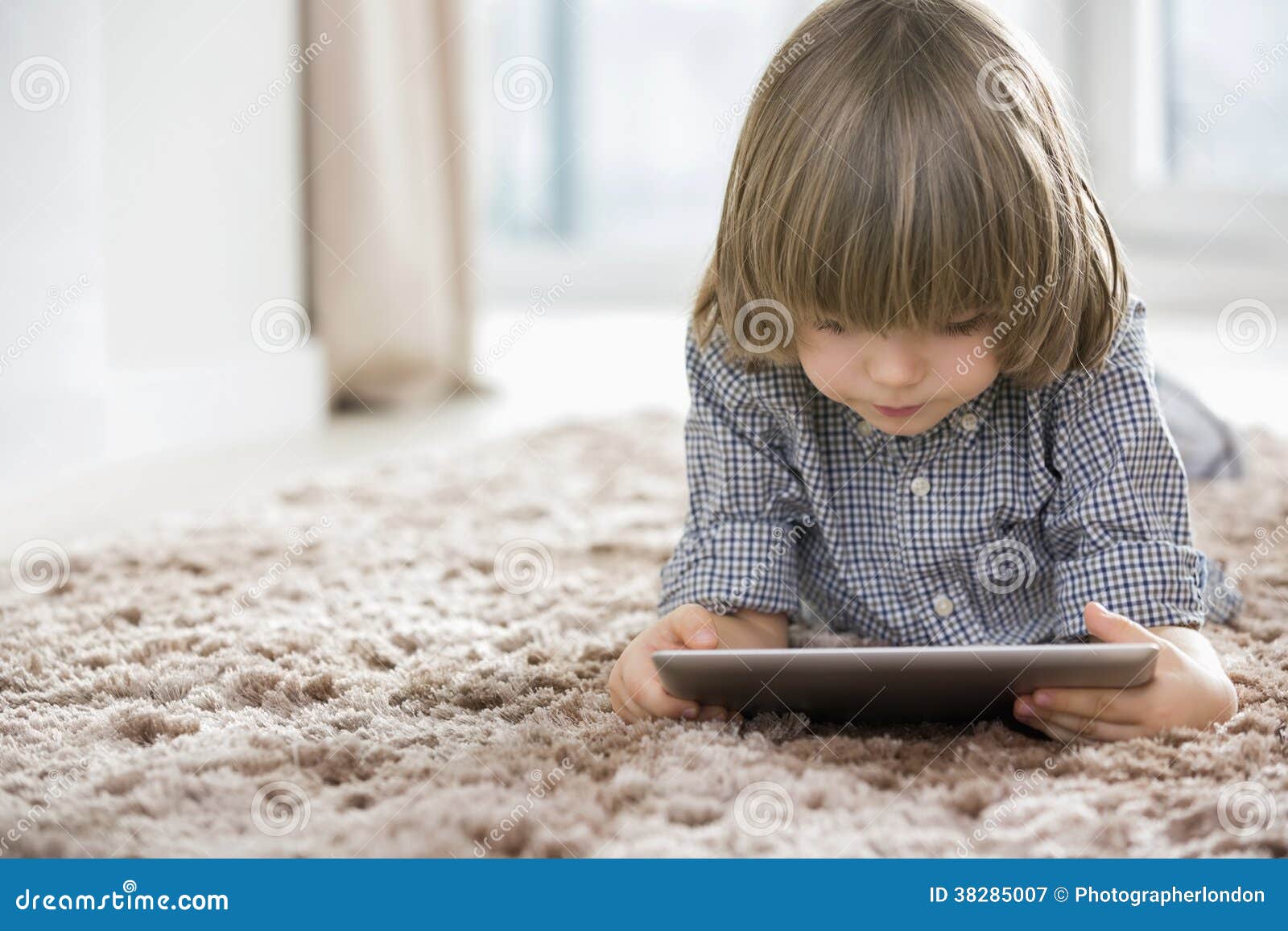 Boy Using Digital Tablet while Lying on Rug at Home Stock Image - Image ...