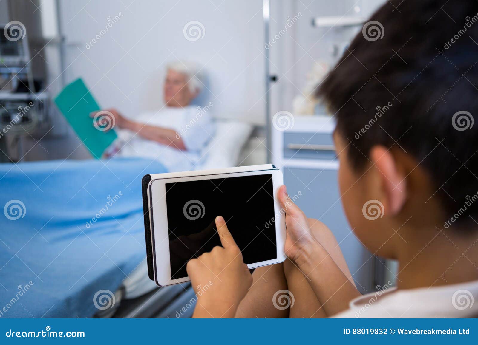 Boy Using Digital Tablet while Senior Patient Reading a Book in the ...
