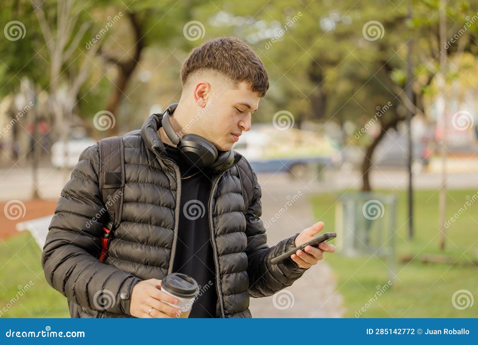 Boy Using His Mobile Phone while Walking through a Public Park Stock ...