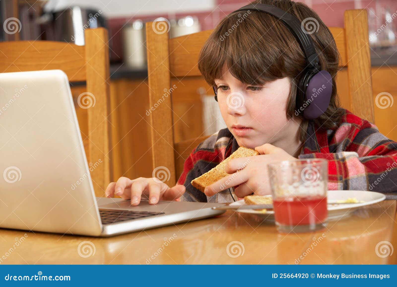 Boy Using Laptop Whilst Eating Breakfast Stock Photo - Image of indoors ...