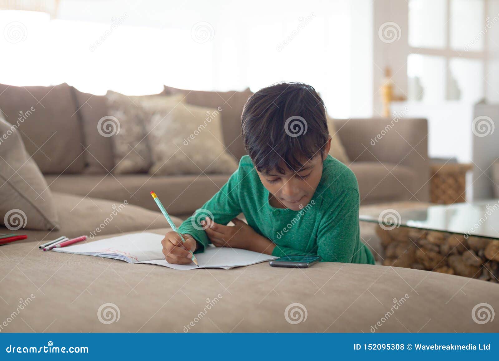 Boy Using Mobile Phone while Drawing a Sketch on Book at Home Stock ...