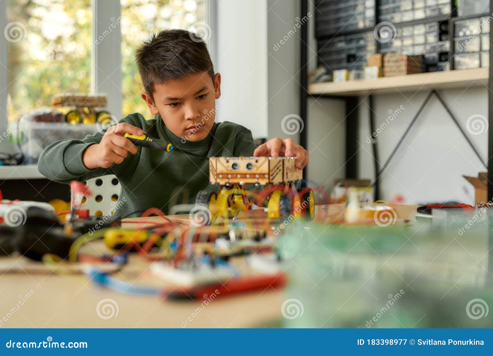 Taking You Forward. Boy Using Screwdriver while Fixing Bolts on a Robot ...