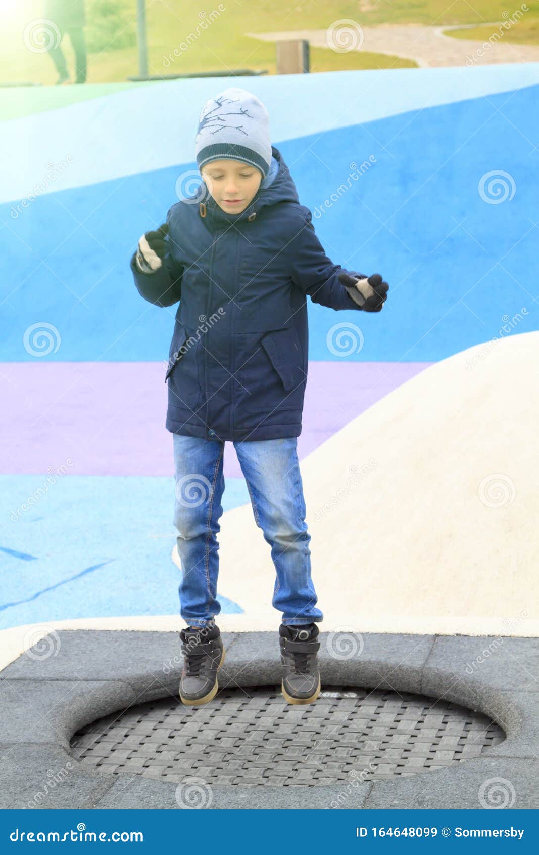 Boy in Warm Clothes Jumping on Trampoline on Modern Playground Outdoors ...