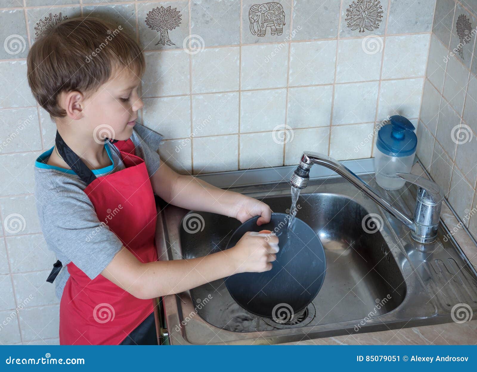 The boy washes dishes stock image. Image of detergent - 85079051