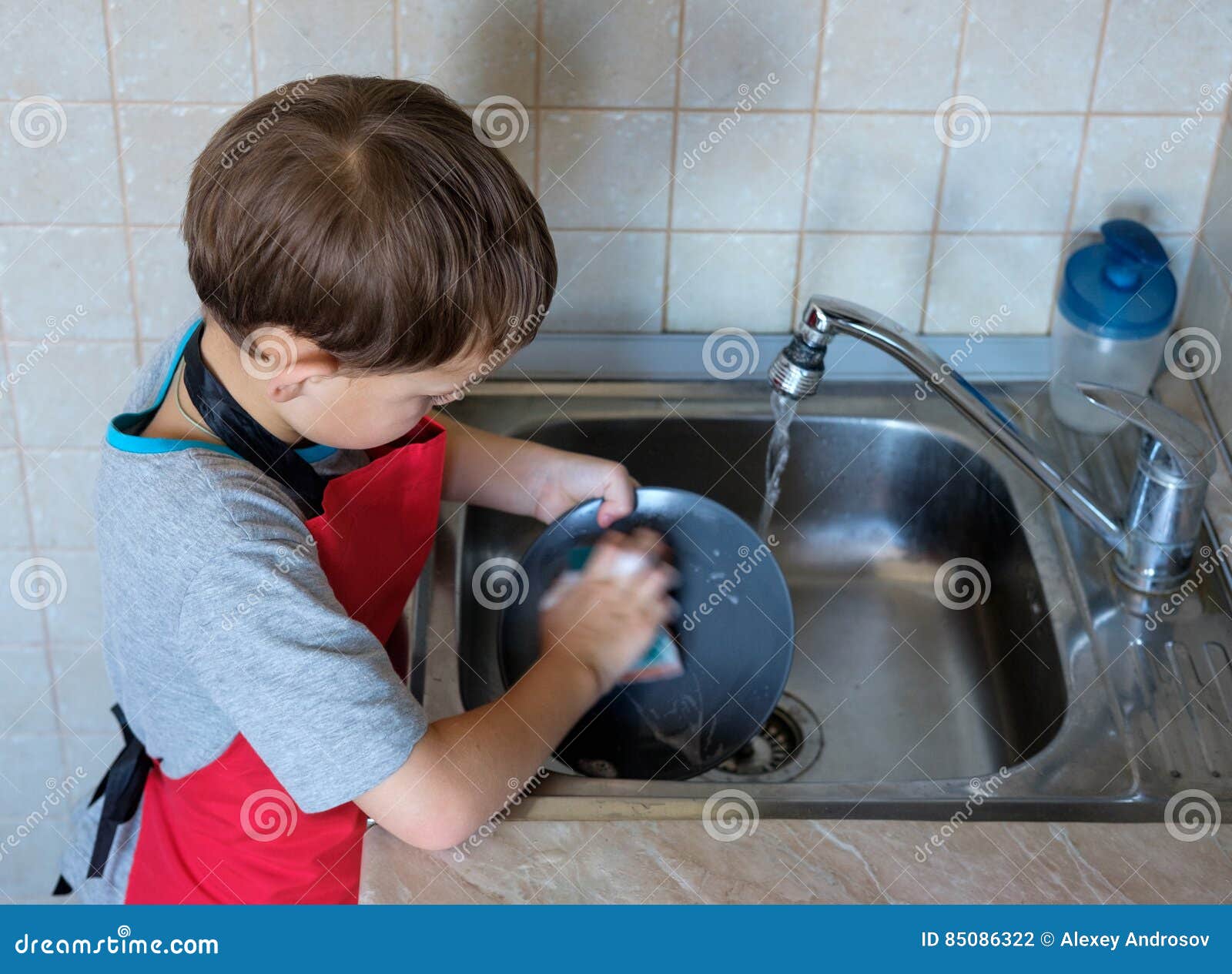 The boy washes dishes stock photo. Image of home, detergent - 85086322
