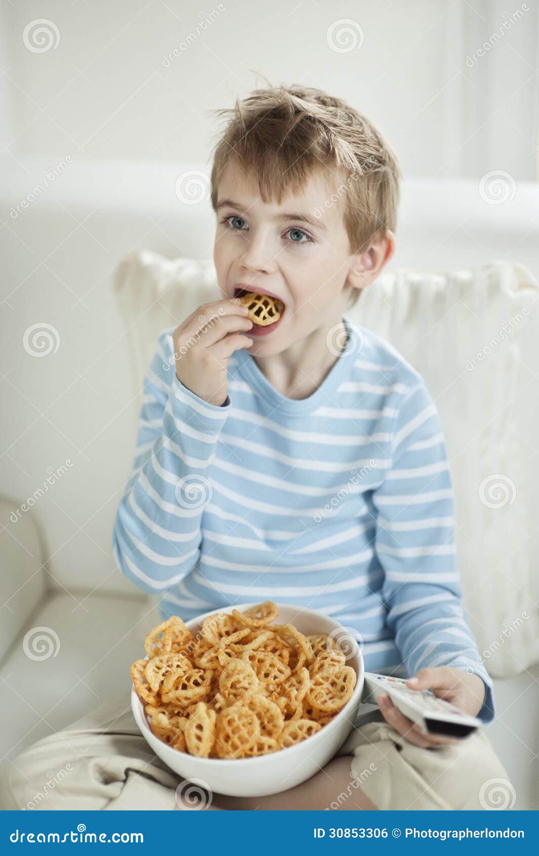 Boy Watching TV while Eating Wheel Shape Snack Pellets Stock Photo ...