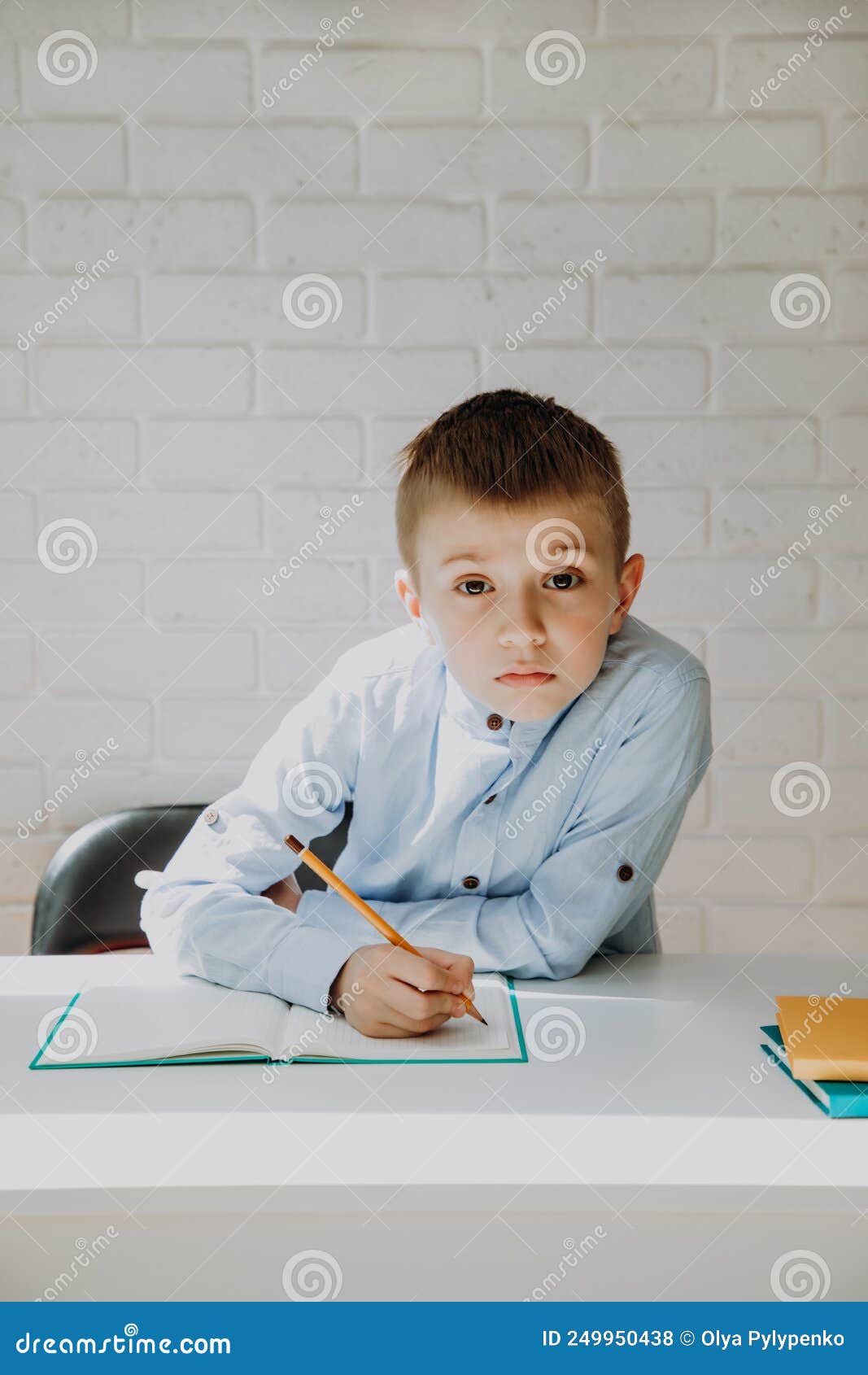 A Boy Writes in a Notebook at a White Desk. Back To School Concept ...