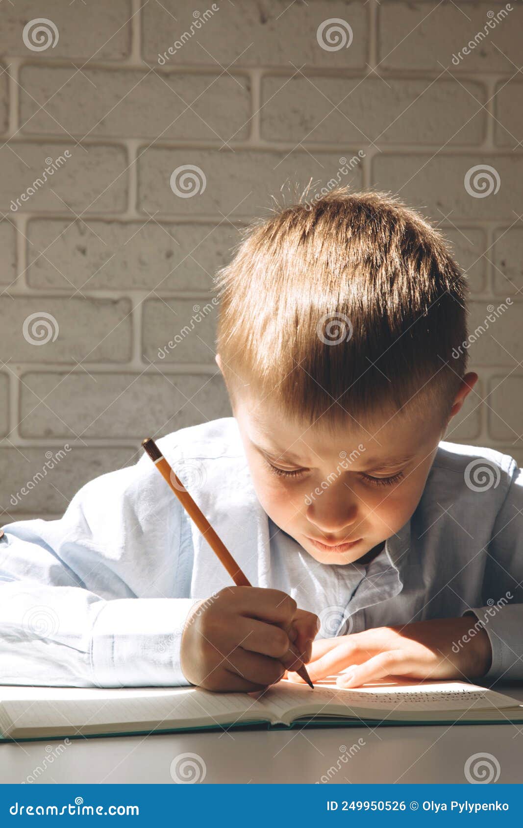 A Boy Writes in a Notebook at a White Desk. Back To School Concept ...