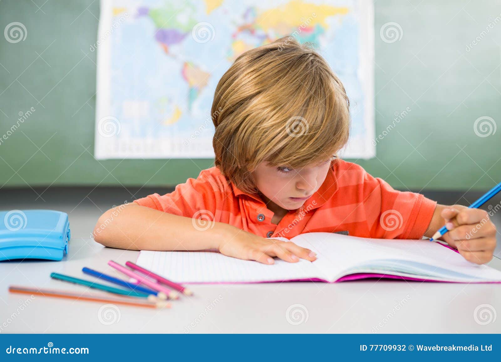 Boy Writing on Book in Classroom Stock Photo - Image of hair, classroom ...