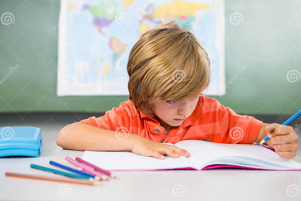 Boy Writing on Book in Classroom Stock Photo - Image of hair, classroom ...