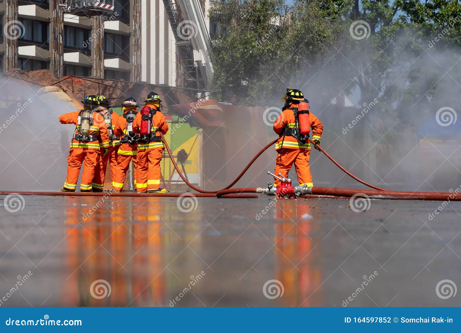 Brave Firefighter Using Extinguisher And Water From Hose For Fire