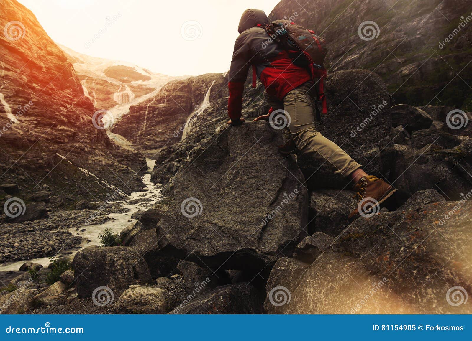 Brave Traveler with a Backpack Climbing on a Rock, Against the Backdrop ...