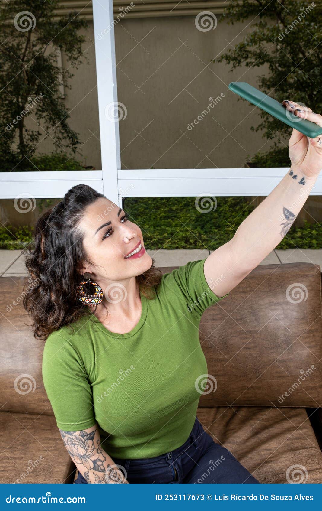 Brazilian Tattooed Woman Making Selfie Sitting On The Brown Sofa
