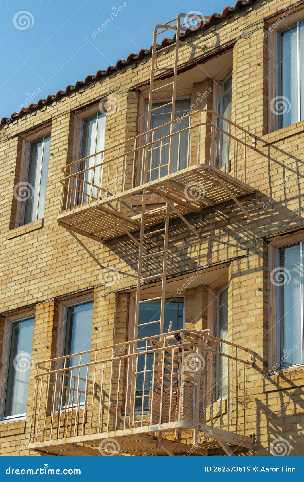 Brick Building Facade with Brown Fire Escape Ladders and Platforms with ...