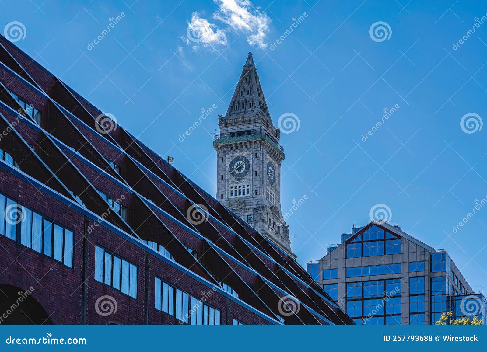 A BRICK CLOCK TOWER with a BRICK BUILDING in FRONT and a MODERN GLASS ...