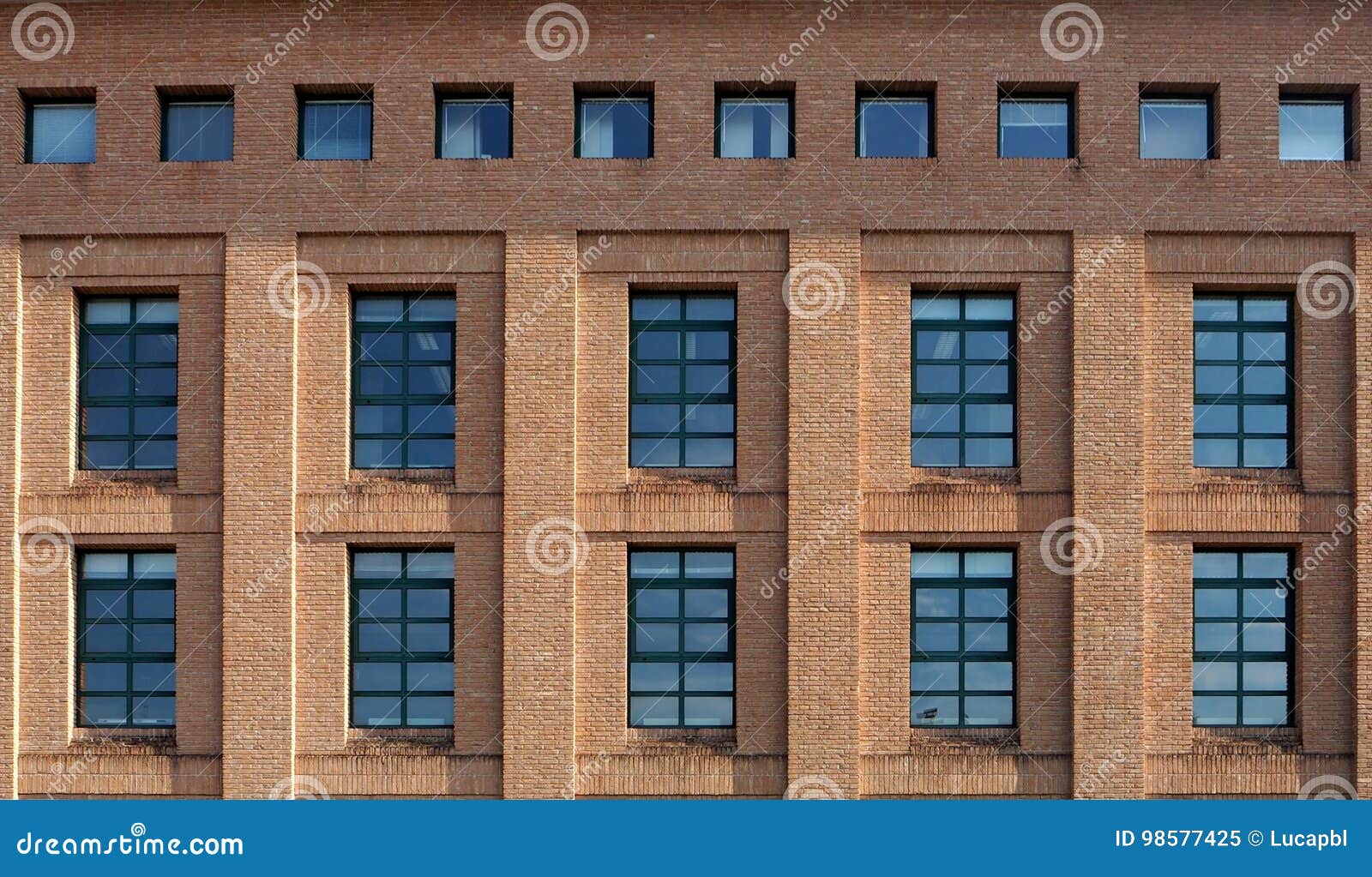 Brick Facade of a Modern Building with Wide Windows and a Row of Small ...