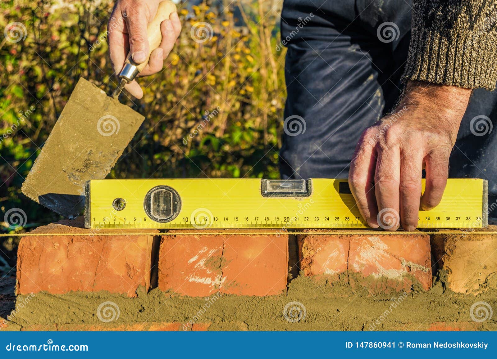 Bricklayer Checks the Horizontal Level of Brick Masonry Wall with a ...