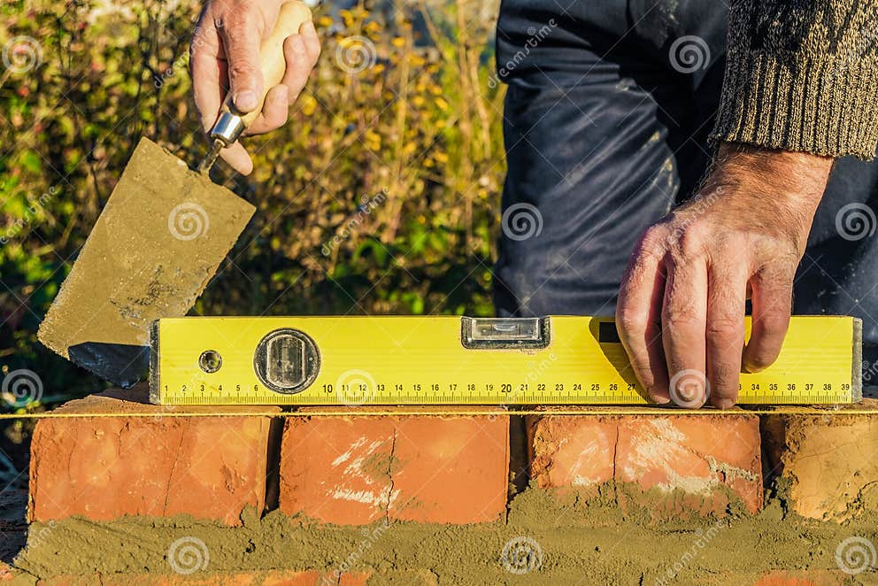 Bricklayer Checks the Horizontal Level of Brick Masonry Wall with a ...