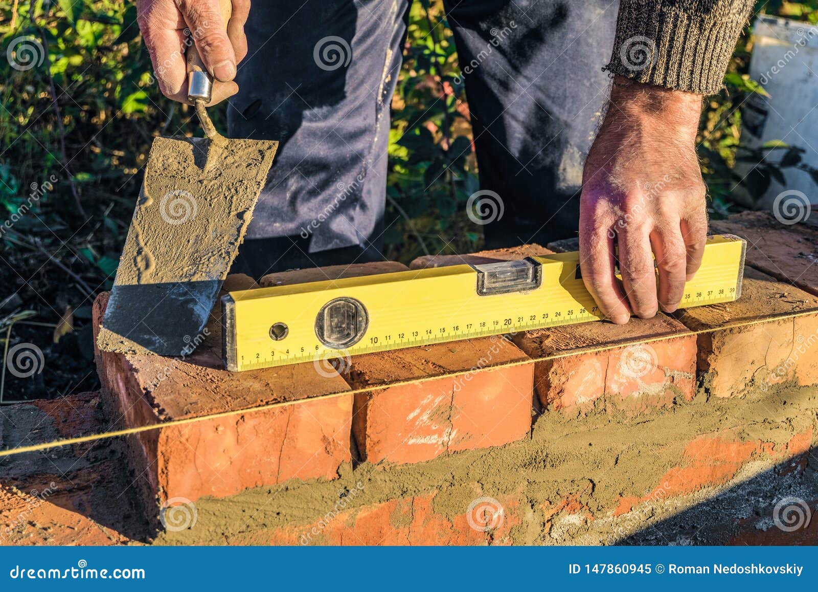 Bricklayer Checks the Horizontal Level of Brick Masonry Wall with a ...
