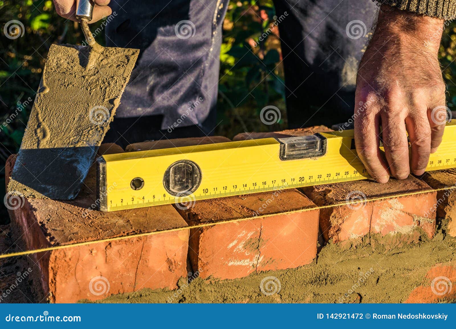 Bricklayer Checks the Horizontal Level of Brick Masonry Wall with a ...