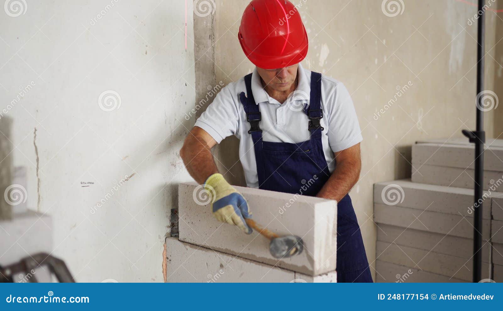 Bricklayer Using Rubber Mallet Hammer To Tap and Level Concrete Blocks ...