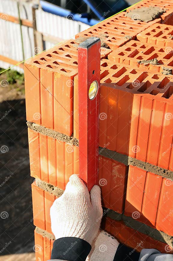 Bricklayer Using a Spirit Level To Check New Brick Wall. Bricklaying ...