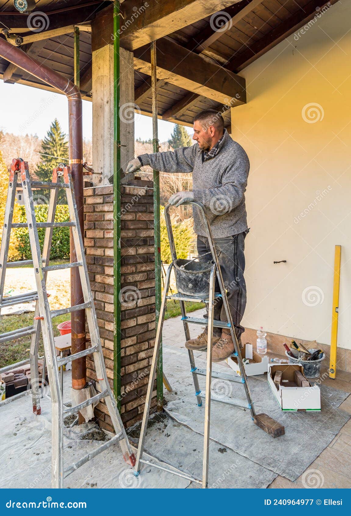 Bricklayer Worker Installing Bricks on the Exterior Concrete Pillar of ...