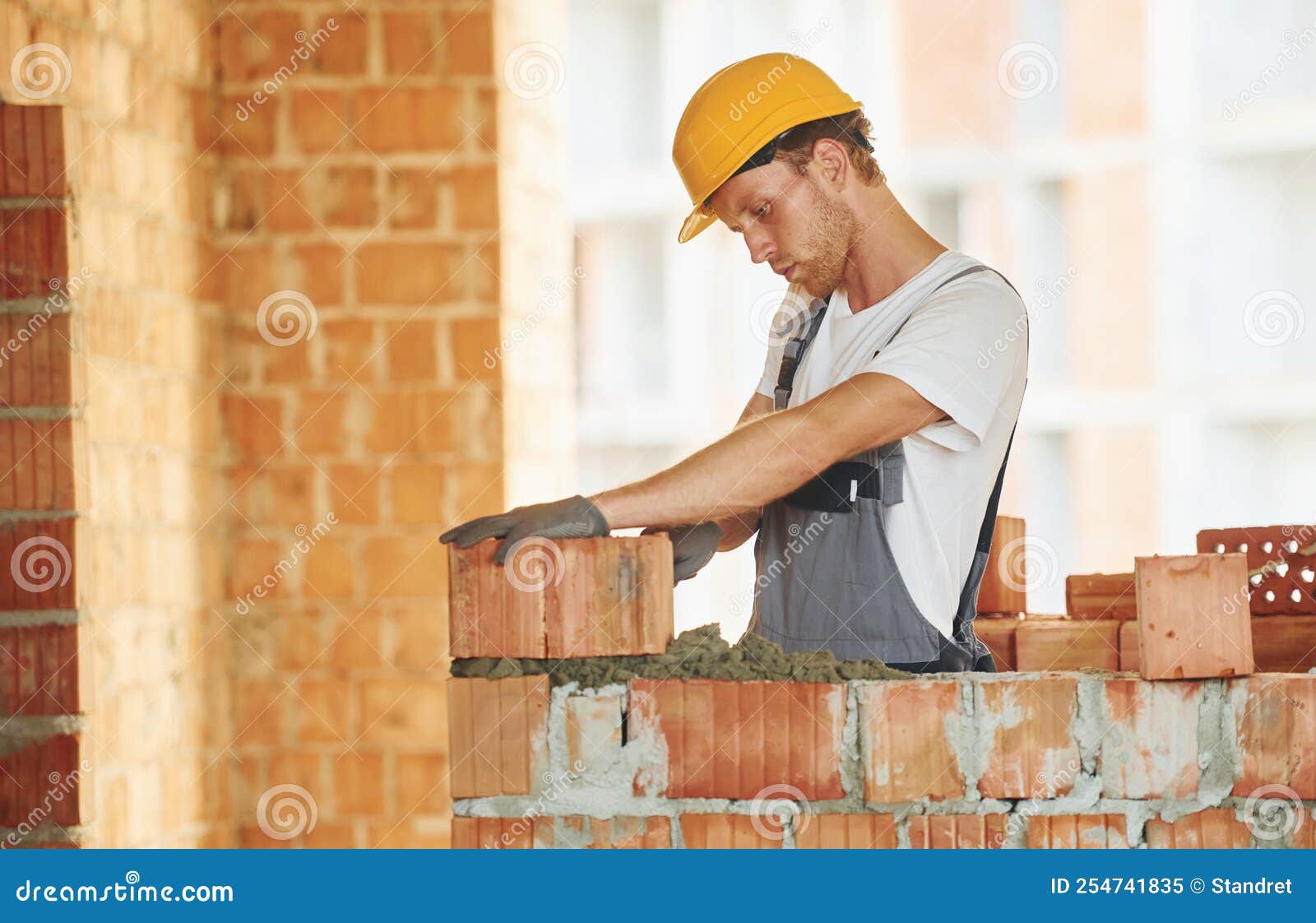 Bricks Installation. Young Man Working in Uniform at Construction at ...